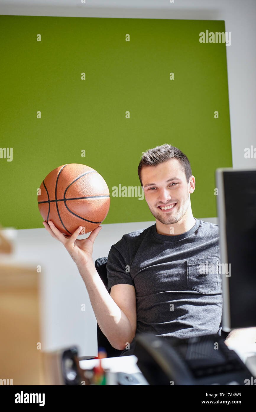 Young man working in office, balancing a basketball Stock Photo - Alamy