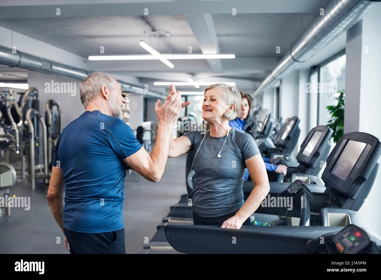 Happy senior man and woman high fiving after working out in gym Stock ...