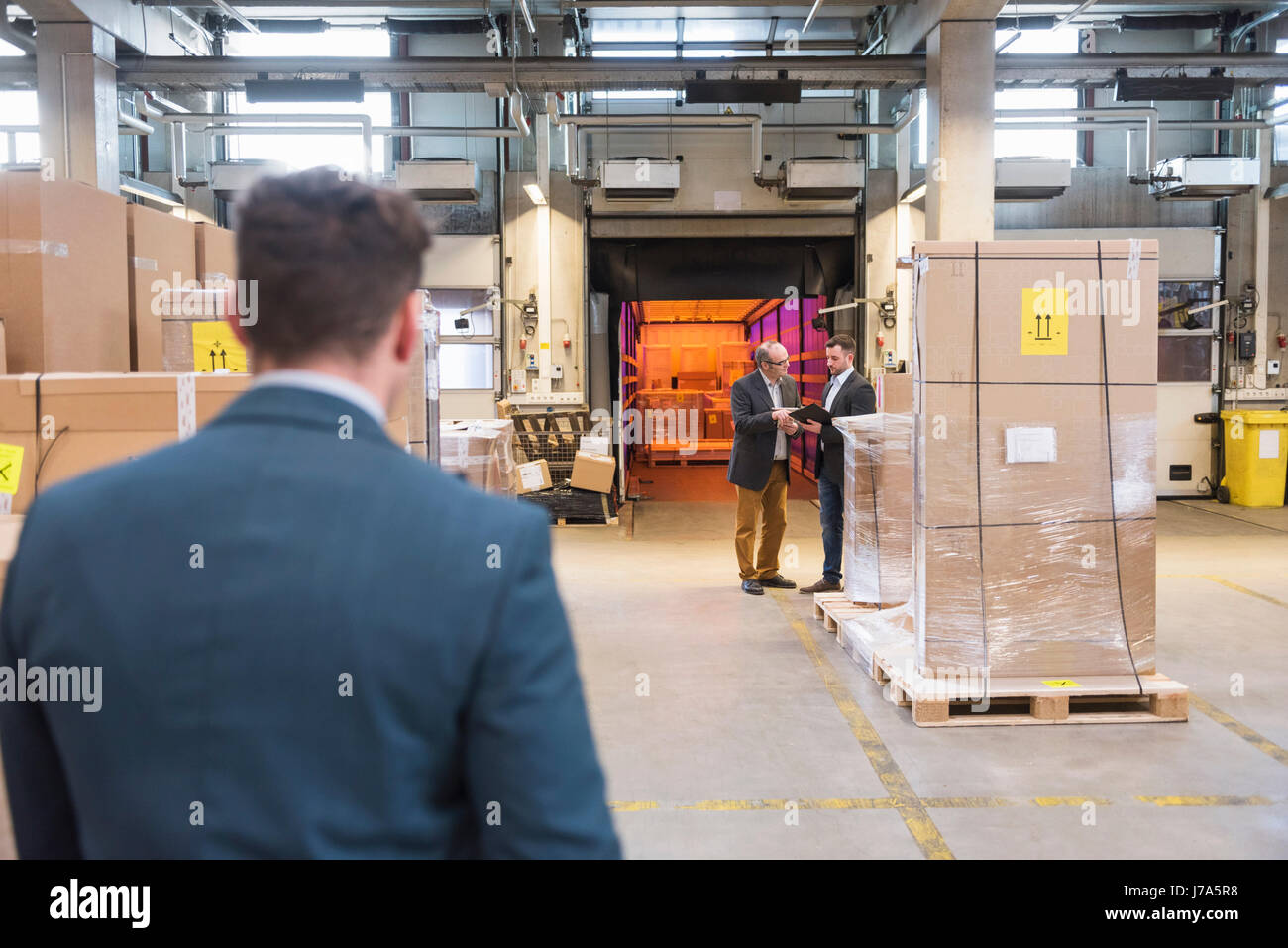 Three men in factory warehouse Stock Photo - Alamy