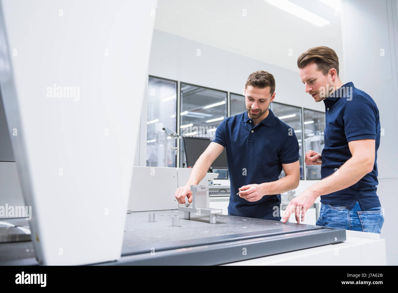 Two men at a machine in testing instrument room Stock Photo - Alamy