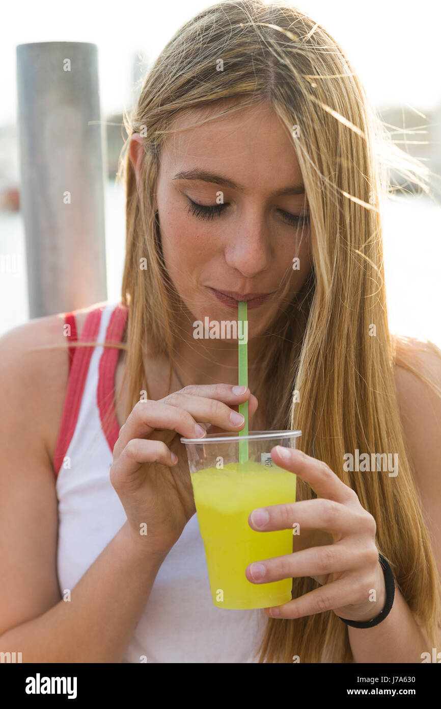 Young woman drinking yellow beverage Stock Photo - Alamy