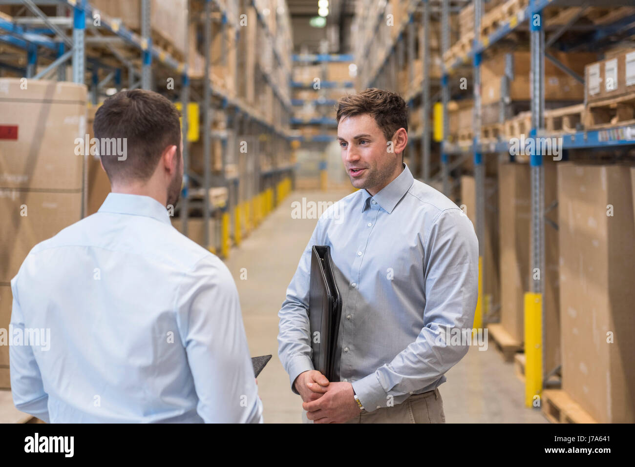 Two men talking in factory warehouse Stock Photo - Alamy