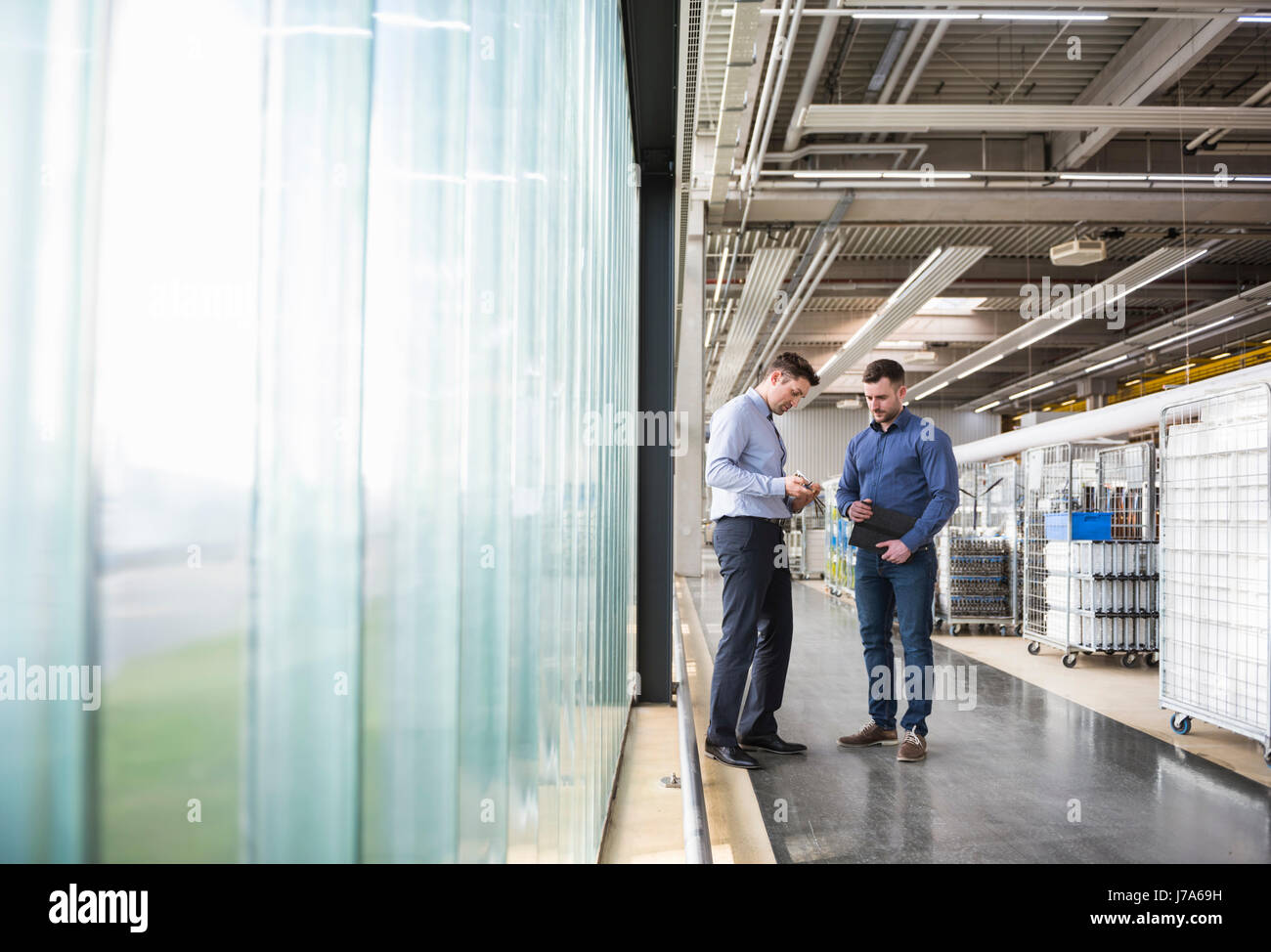Two men in factory shop floor examining product Stock Photo - Alamy