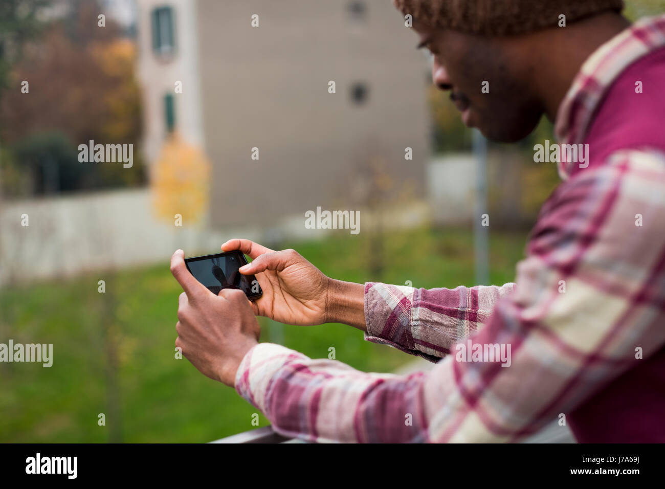 Young man holding cell phone outdoors Stock Photo - Alamy