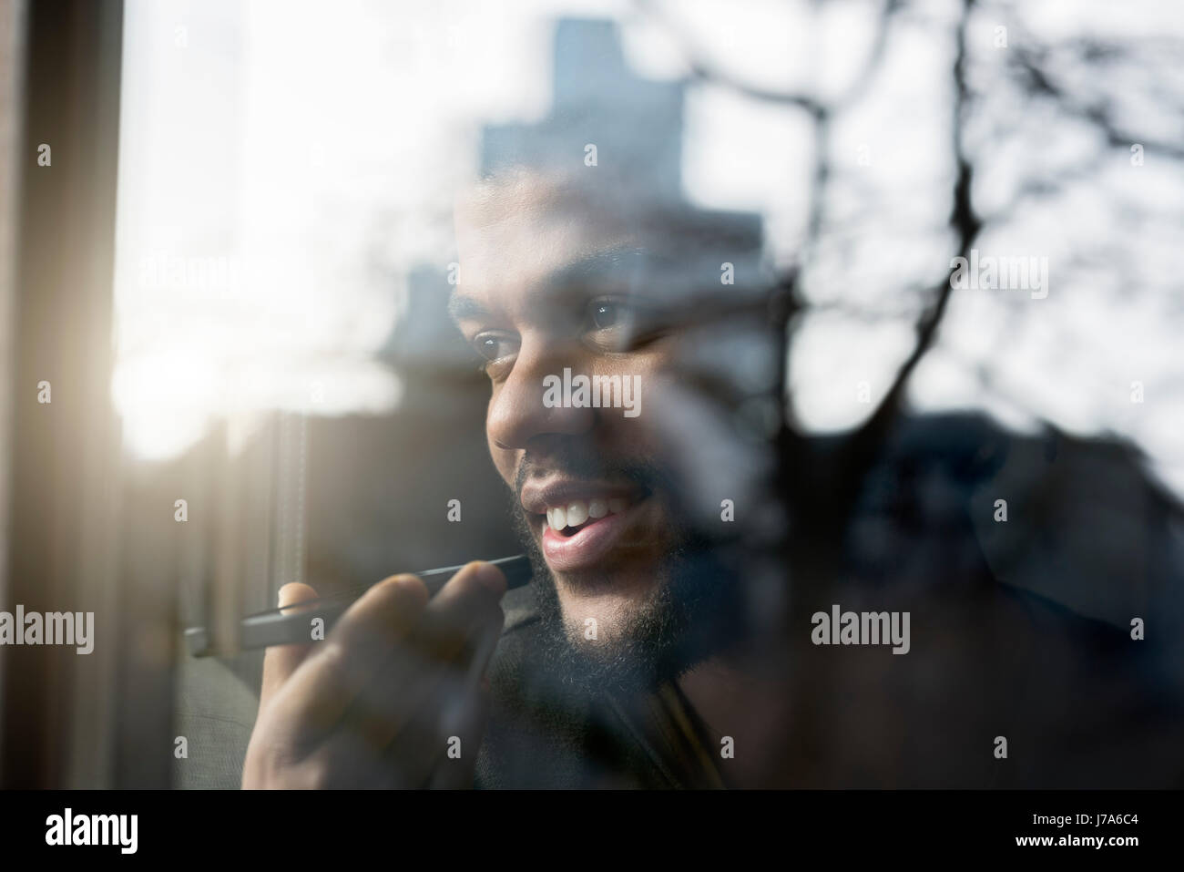 Man at window looking outside talking into smartphone Stock Photo - Alamy