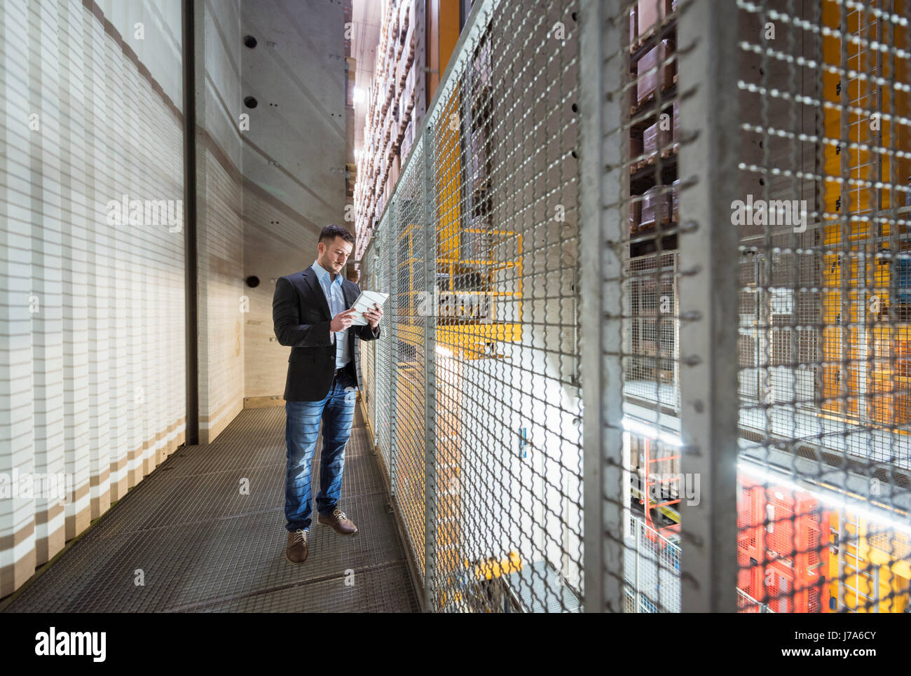Man in automatized high rack warehouse looking at tablet Stock Photo ...