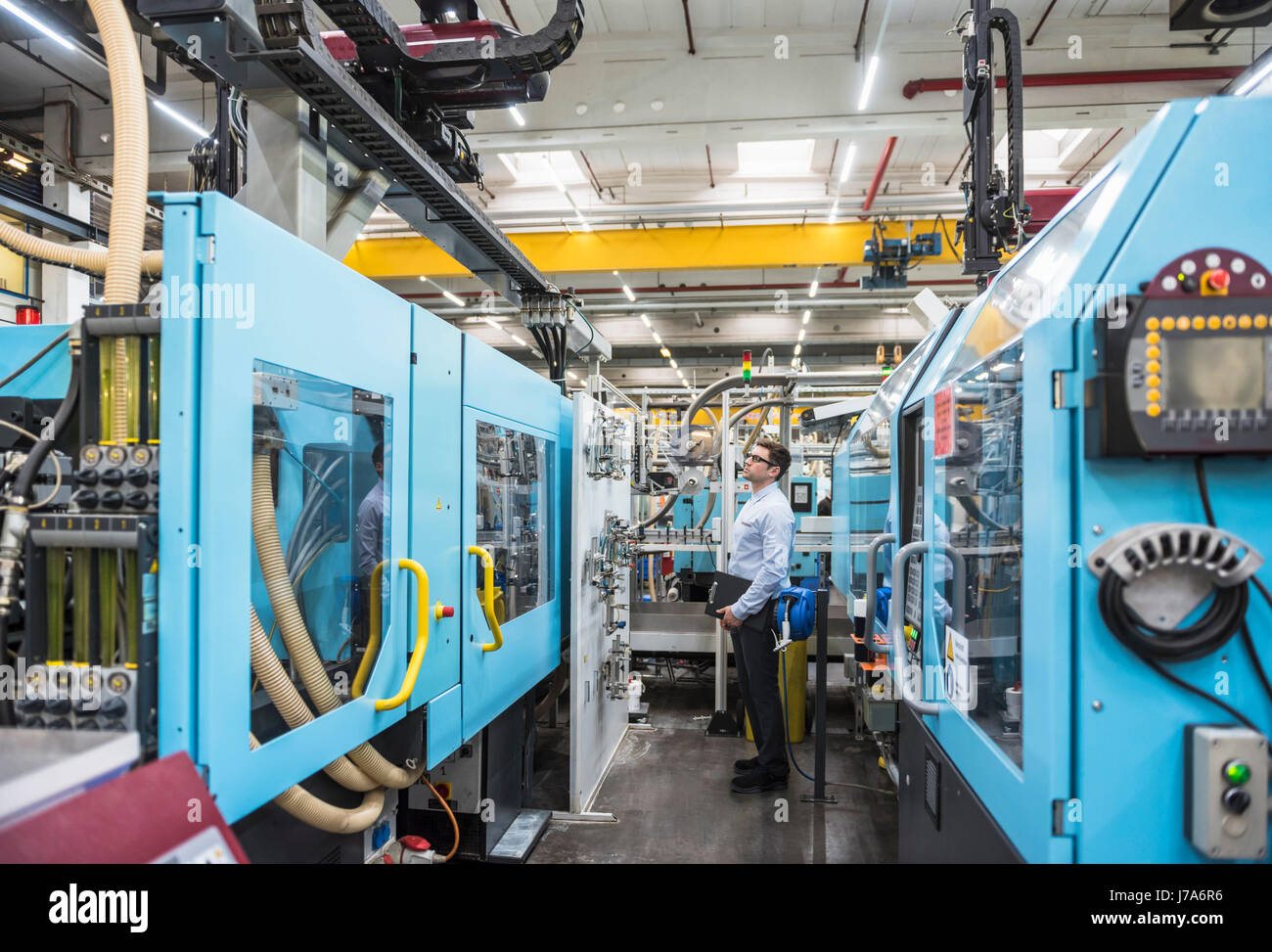 Man with documents standing among machines in factory shop floor Stock ...