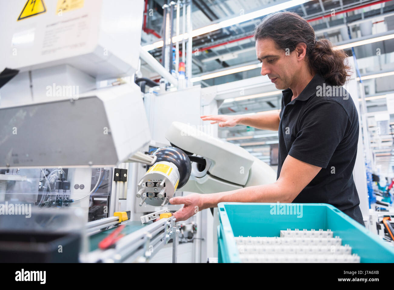 Man operating assembly robot in factory Stock Photo - Alamy