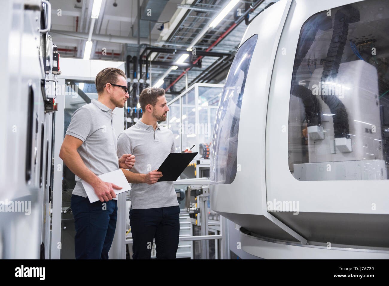 Two men looking at machine in factory shop floor Stock Photo - Alamy
