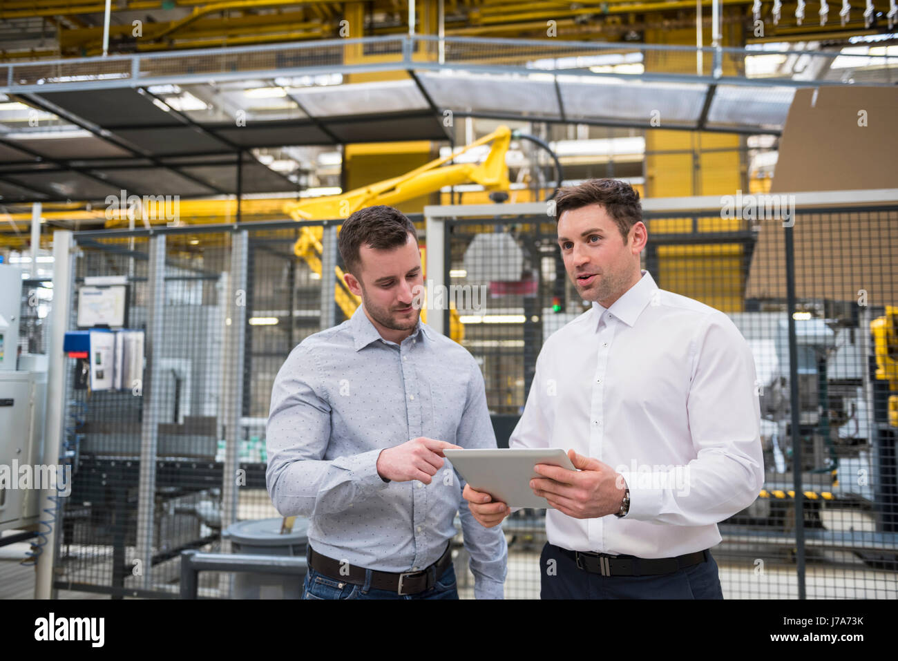 Two men with tablet talking in factory shop floor Stock Photo - Alamy