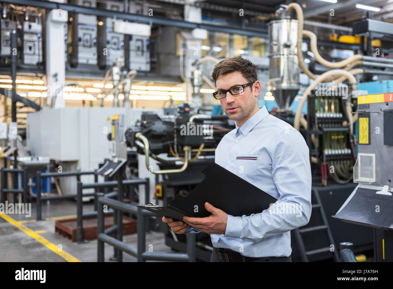 Portrait of man holding documents in factory shop floor Stock Photo - Alamy