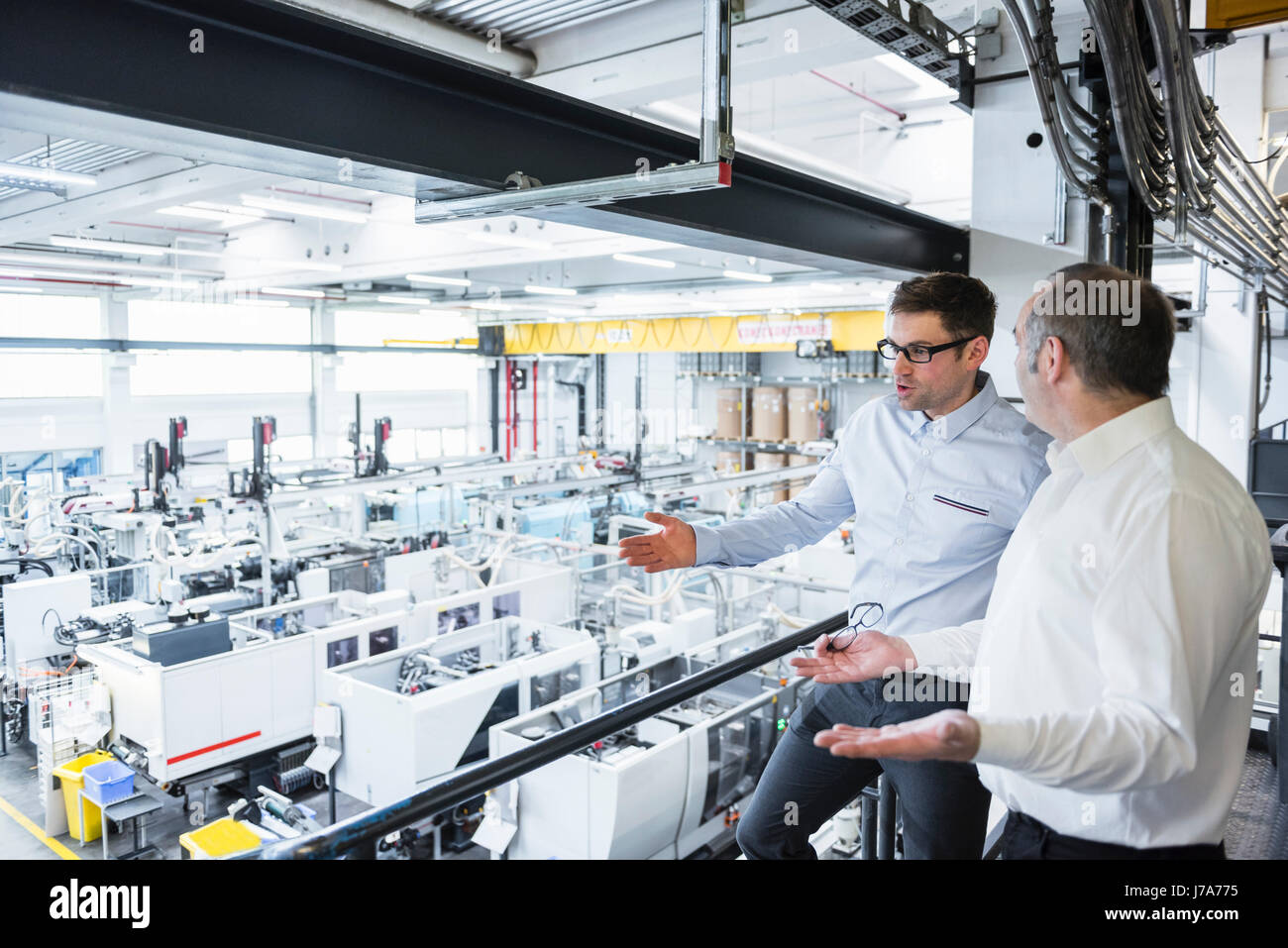 Two men talking in factory shop floor Stock Photo - Alamy