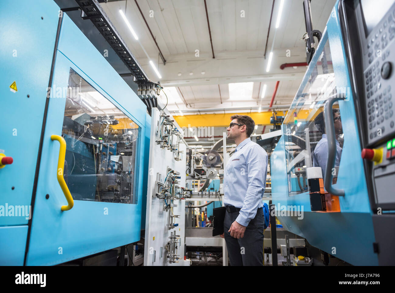 Man with documents standing among machines in factory shop floor Stock ...