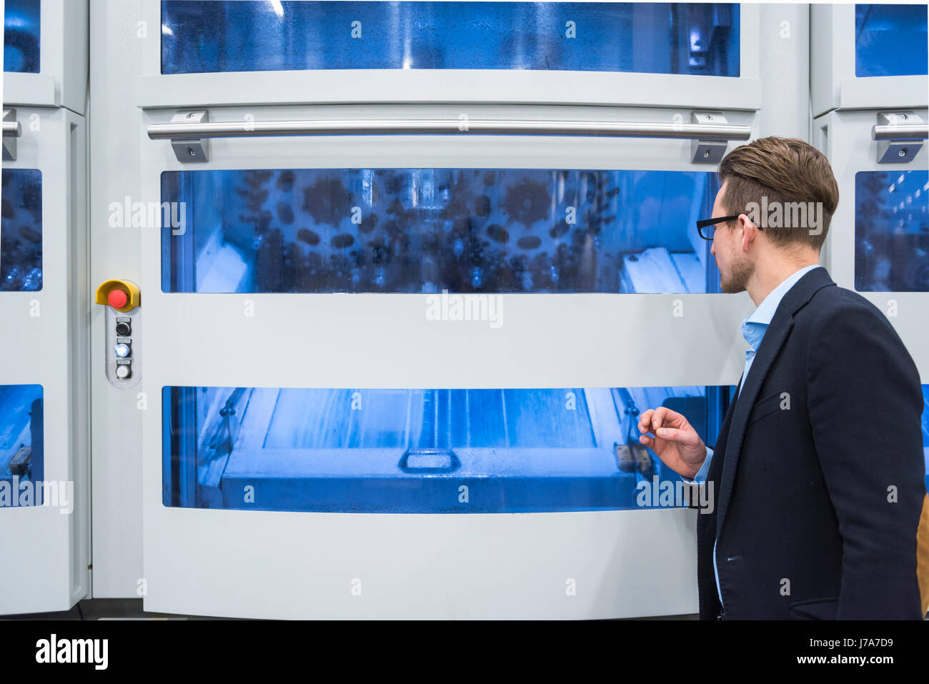 Man looking at machine in factory shop floor Stock Photo - Alamy