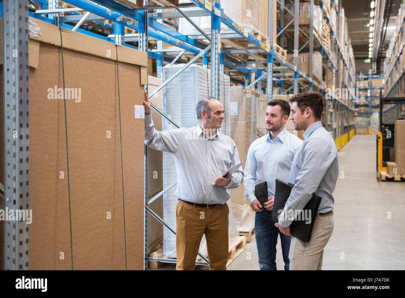 Three men with tablet talking in factory warehouse Stock Photo - Alamy