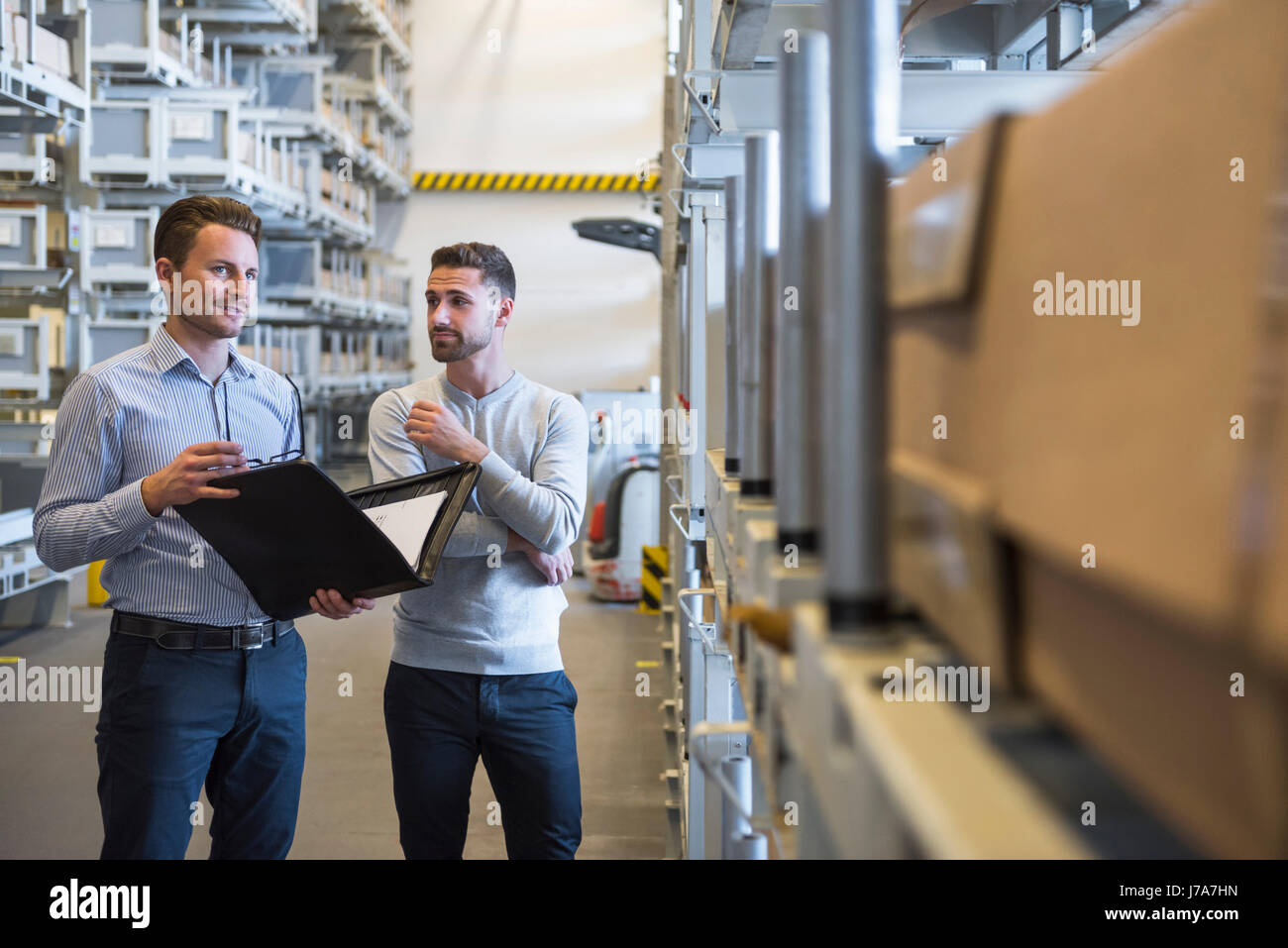 Two men standing in factory warehouse Stock Photo - Alamy