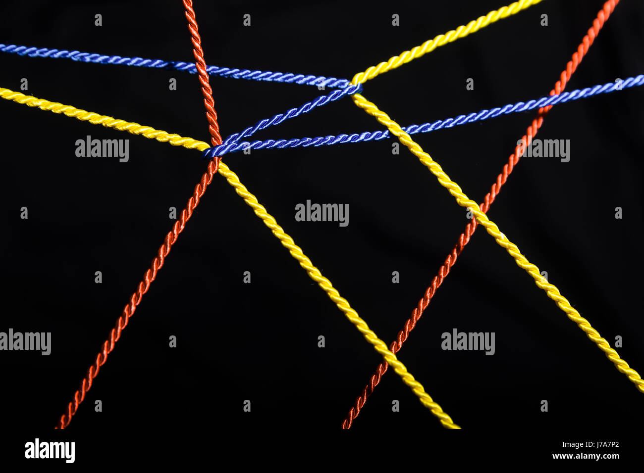 Connected ropes in front of black background Stock Photo - Alamy