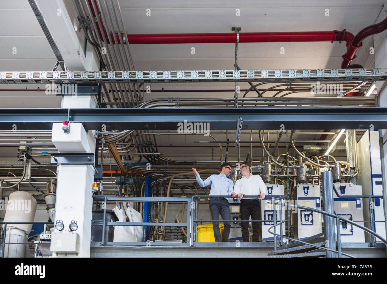 Two men talking in factory shop floor Stock Photo - Alamy