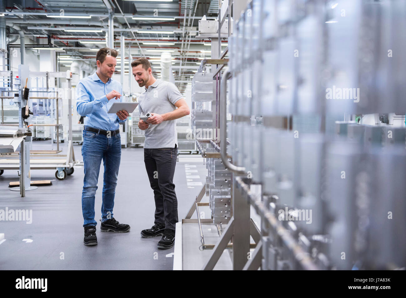 Two men with tablet talking in factory shop floor Stock Photo - Alamy