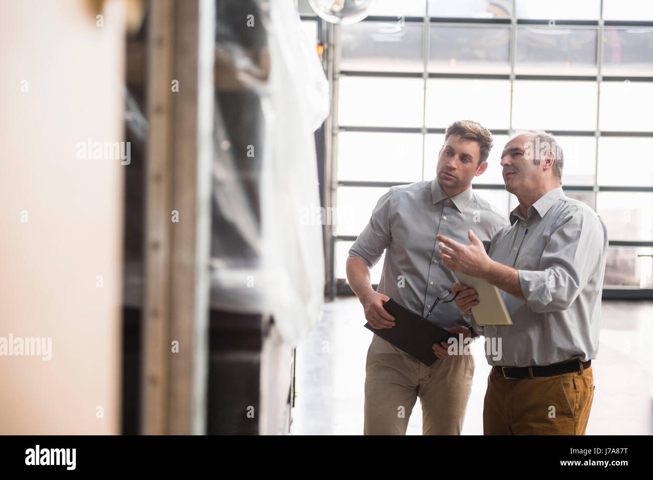 Two men talking in factory warehouse Stock Photo - Alamy