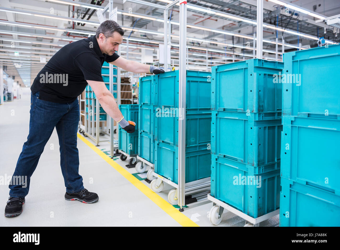 Man scanning boxes on tugger train in industrial hall Stock Photo - Alamy