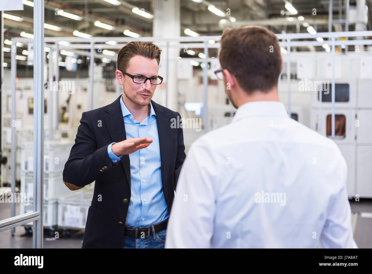 Two men talking in factory shop floor Stock Photo - Alamy