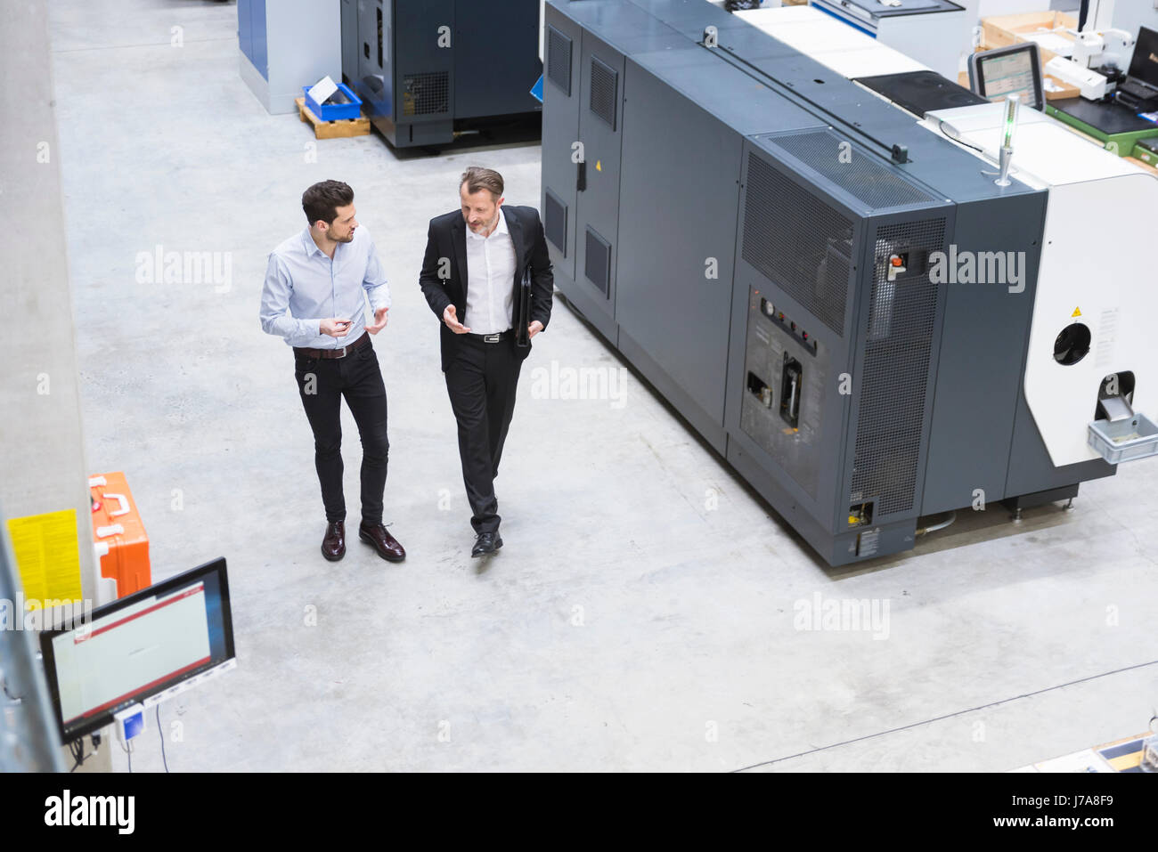 Two businessman observing industrial robots in factory Stock Photo - Alamy