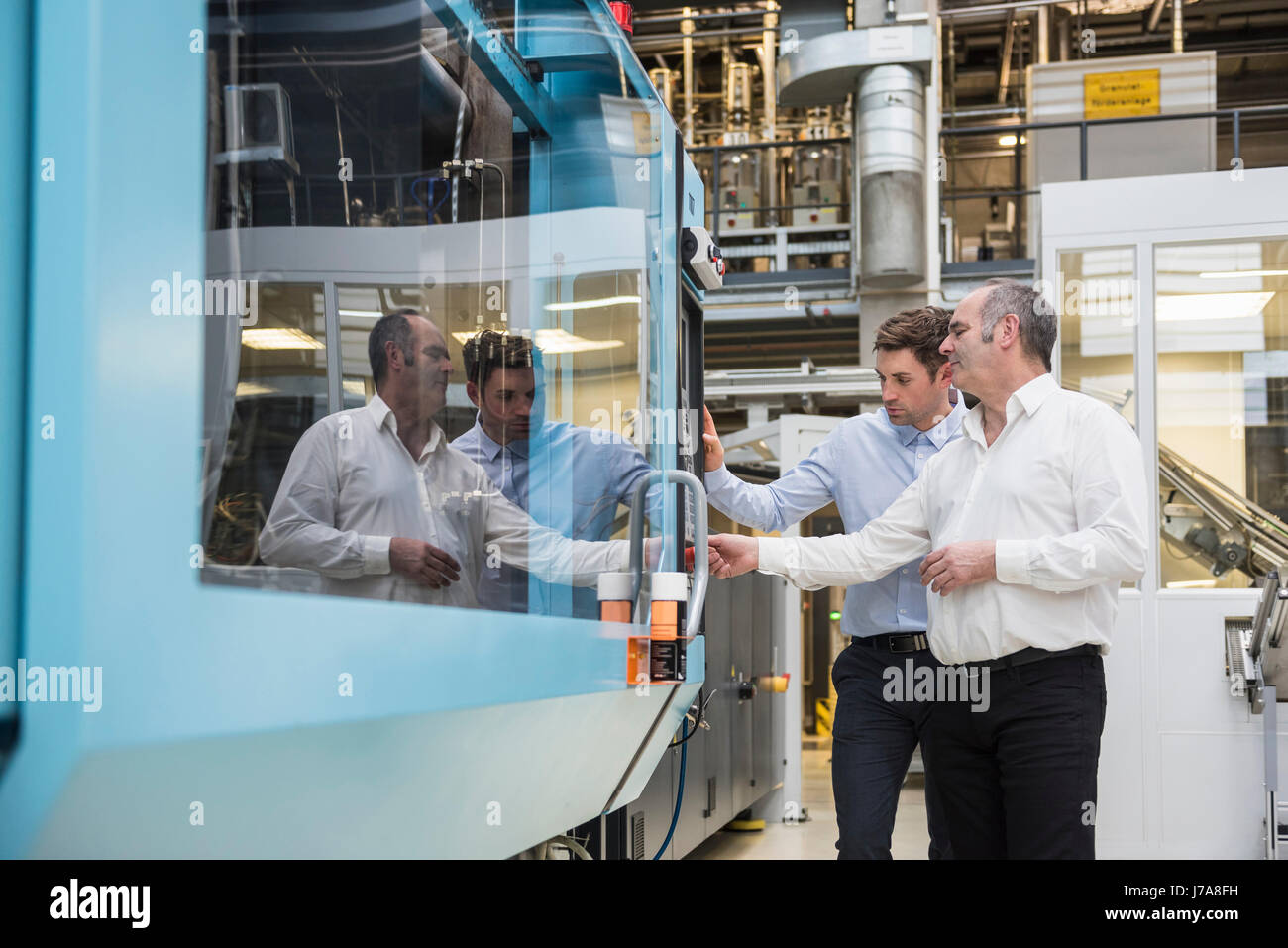 Two men looking at machine in factory shop floor Stock Photo - Alamy
