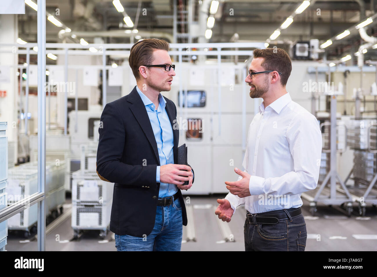 Two men talking in factory shop floor Stock Photo - Alamy