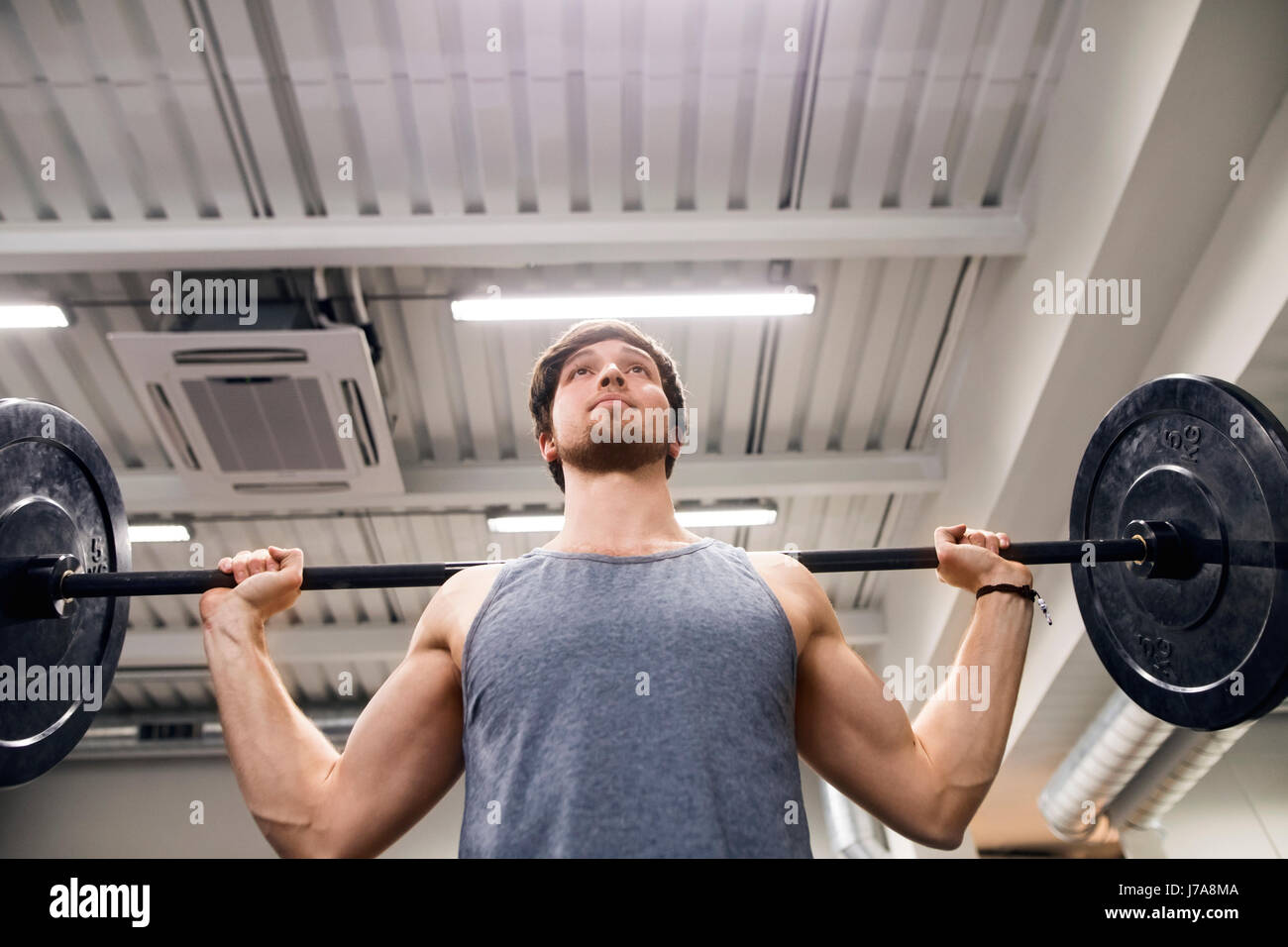 Young man lifting barbell Stock Photo - Alamy