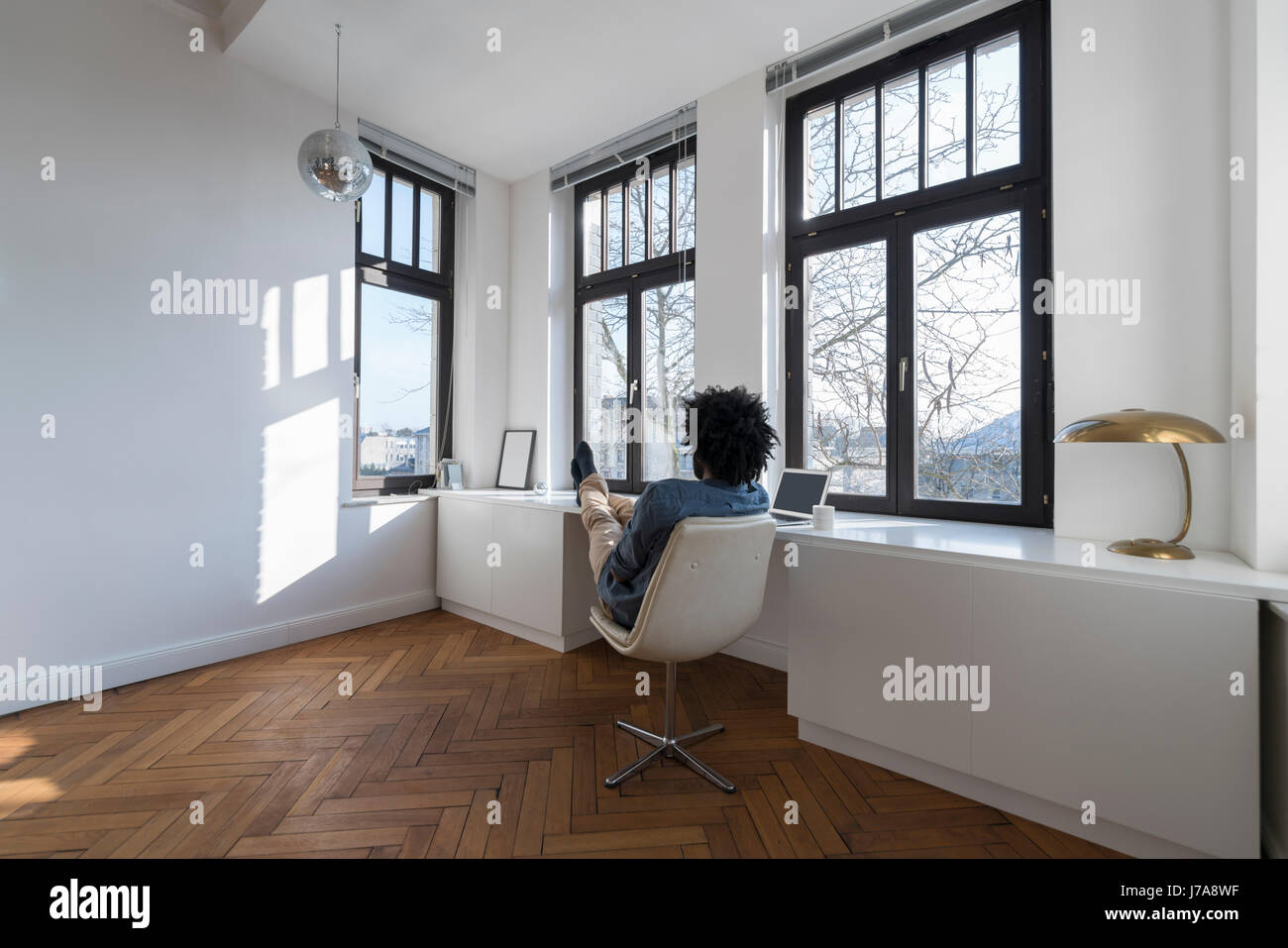 Man sitting in minimalist empty room on chair Stock Photo - Alamy