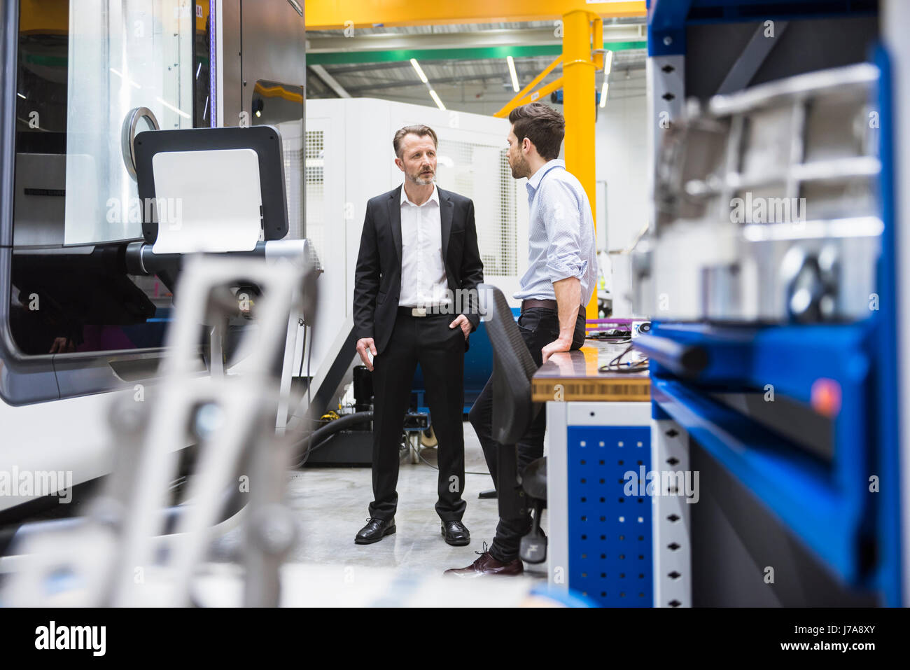 Two men talking in factory shop floor Stock Photo - Alamy
