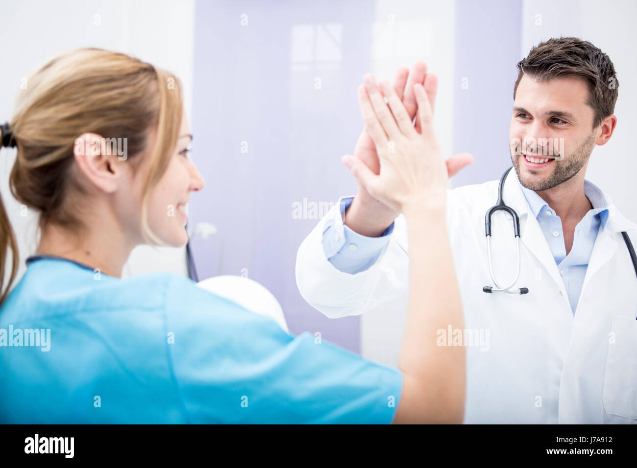 Two smiling doctors high fiving Stock Photo - Alamy