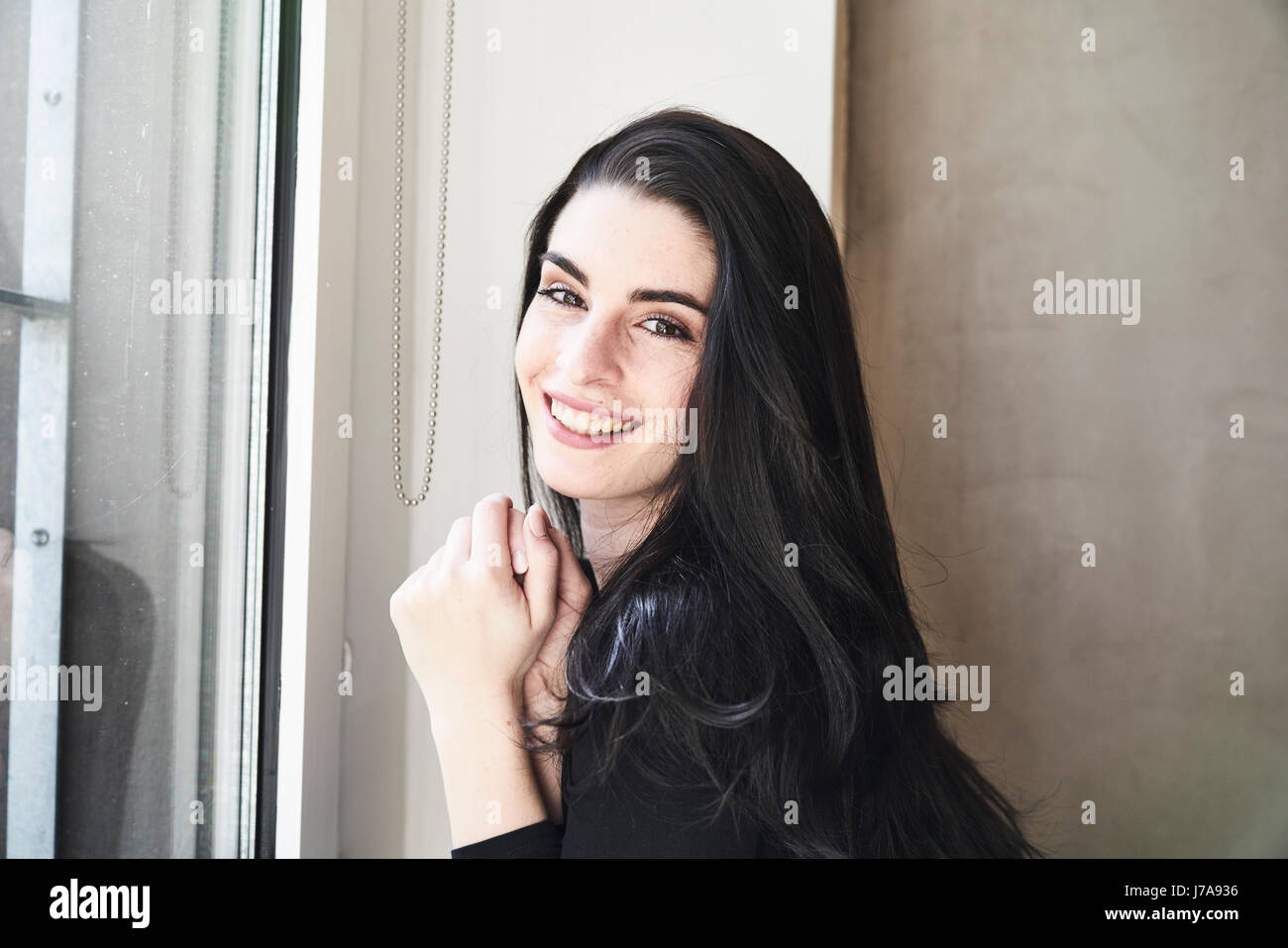 Portrait of smiling young woman at the window Stock Photo - Alamy
