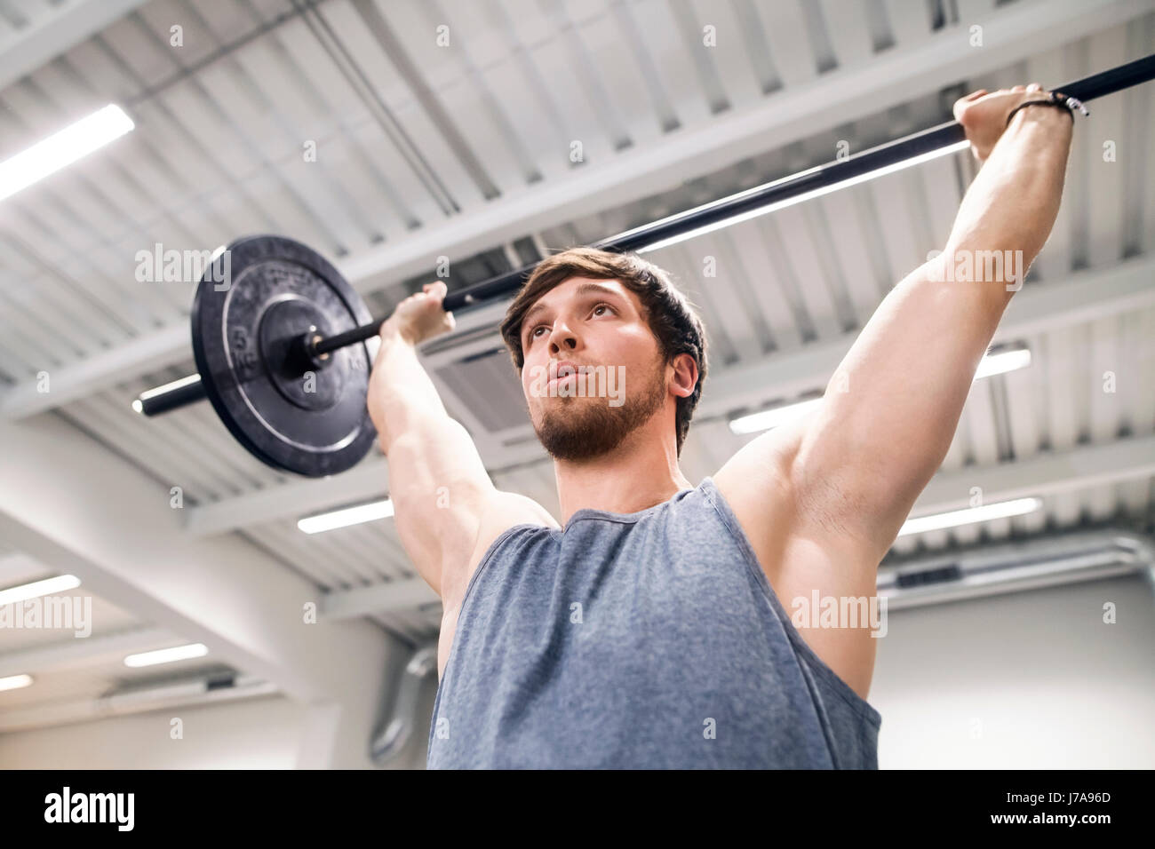 Young man lifting barbell Stock Photo - Alamy