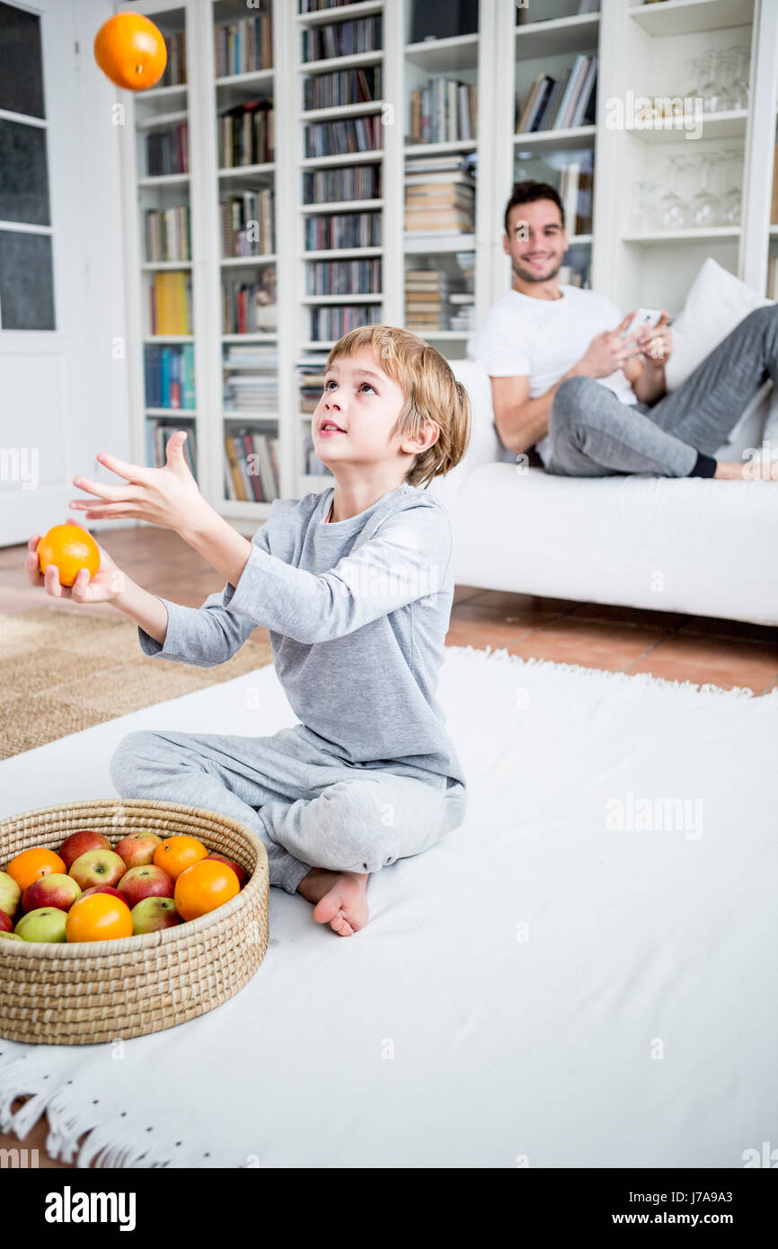 Boy juggling with oranges at home Stock Photo - Alamy