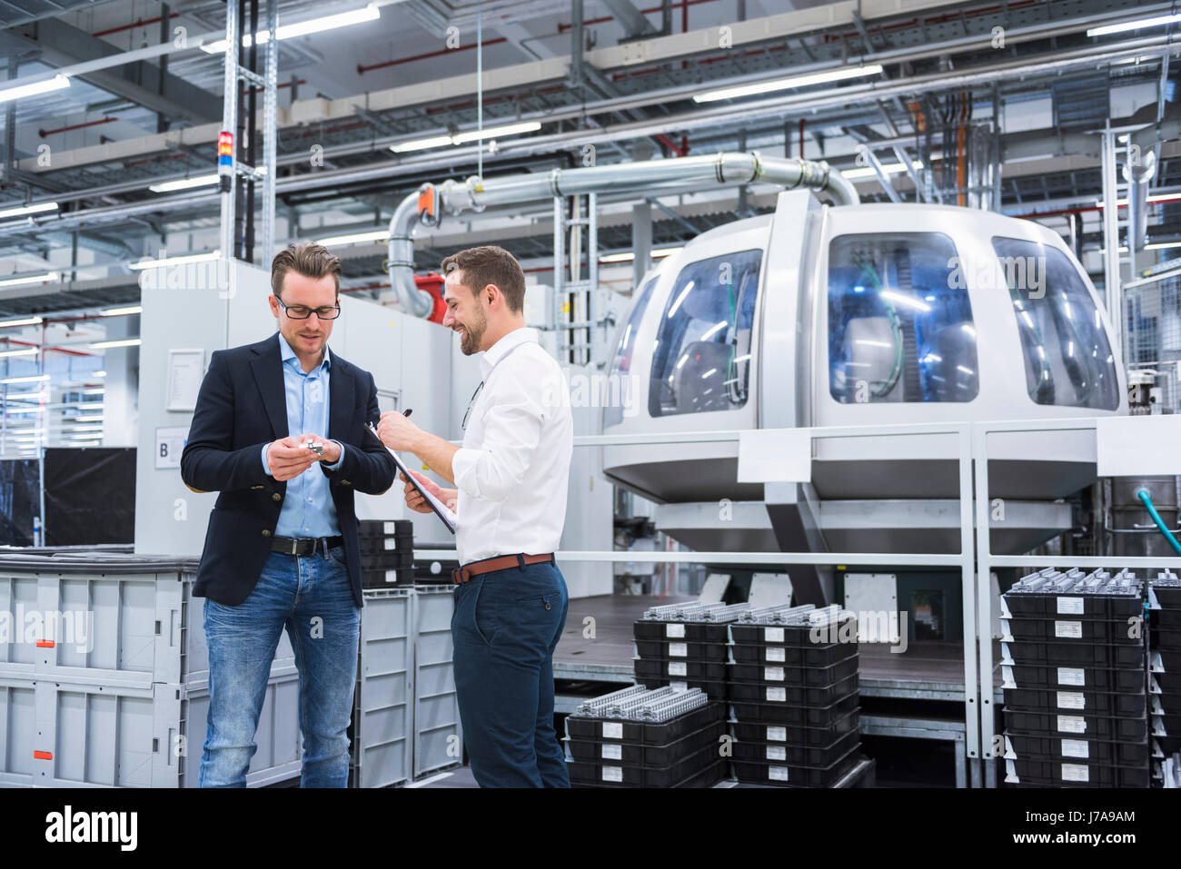 Two men in factory shop floor examining product Stock Photo - Alamy