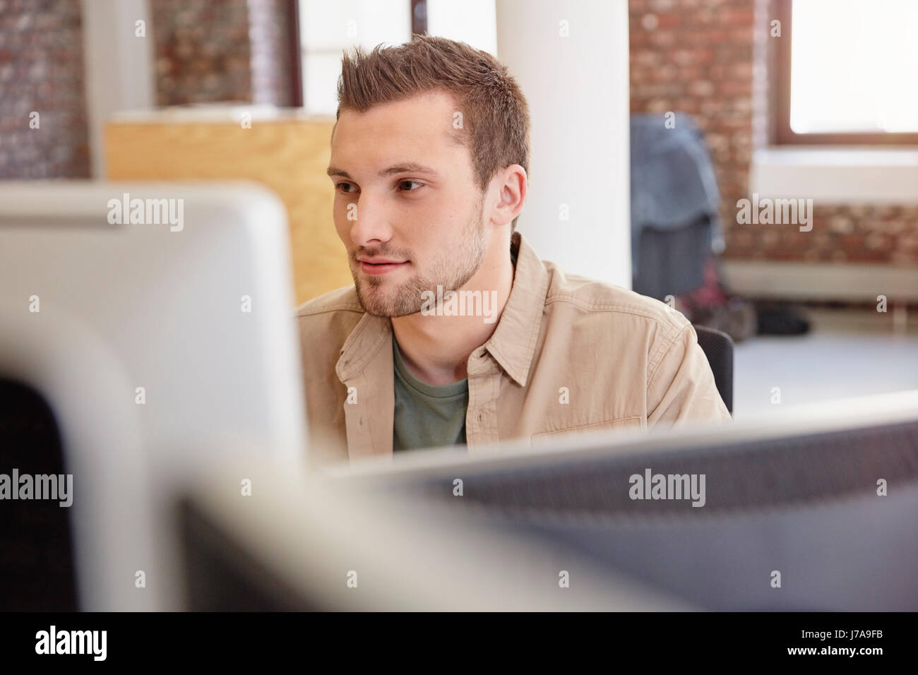 Young man sitting in office using computer Stock Photo - Alamy