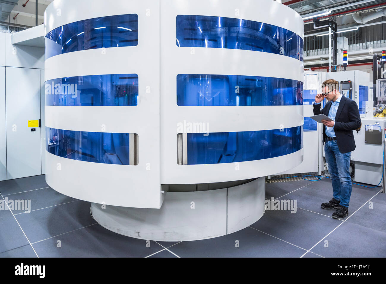 Man holding tablet looking at machine in factory shop floor Stock Photo ...