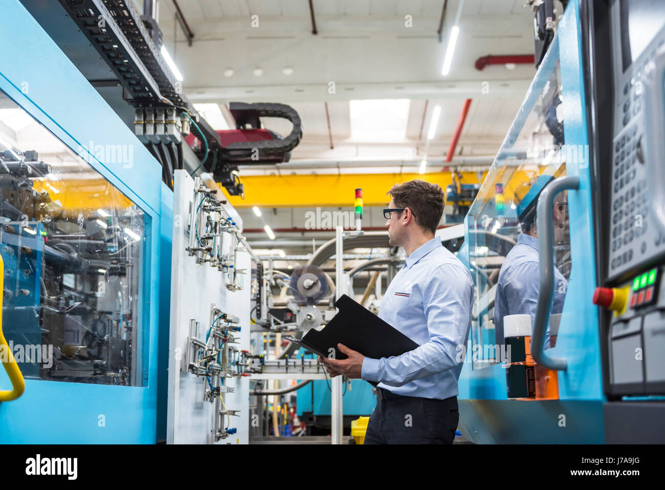 Man with documents standing among machines in factory shop floor Stock ...