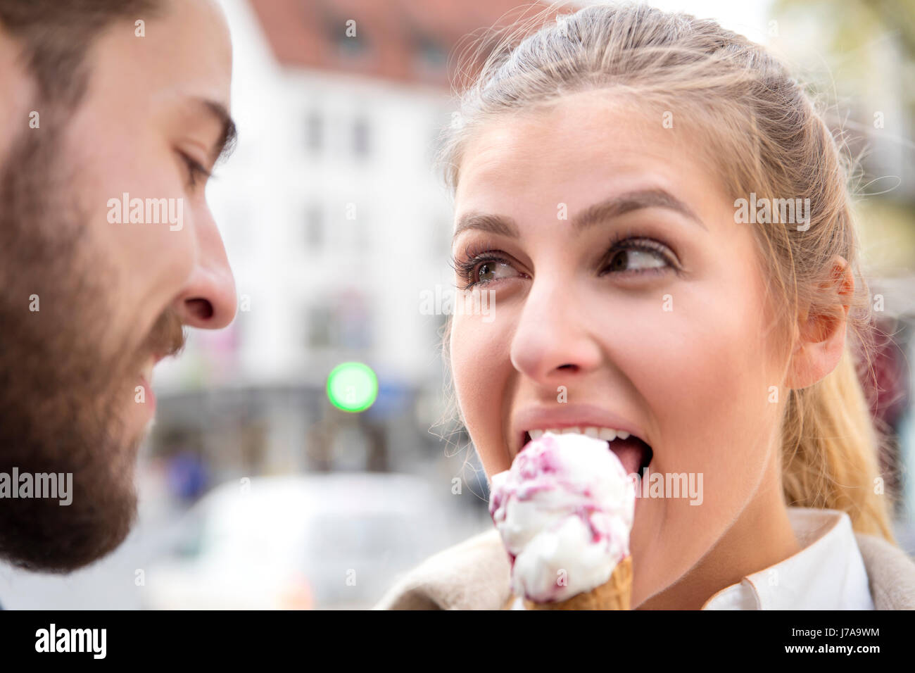 Portrait of young woman eating ice cream with her boyfriend Stock Photo ...