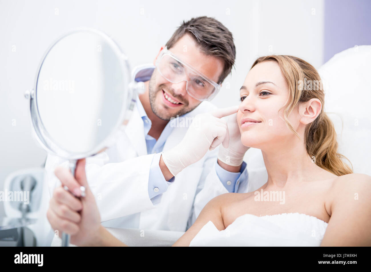 Aesthetic surgery, woman looking in mirror Stock Photo - Alamy
