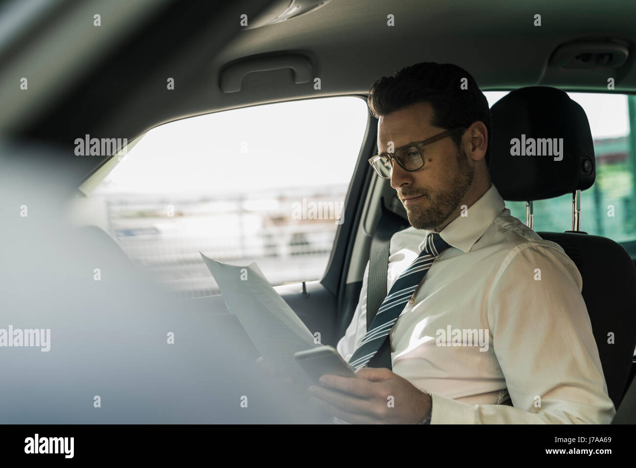Successful businessman sitting in car reading files Stock Photo - Alamy