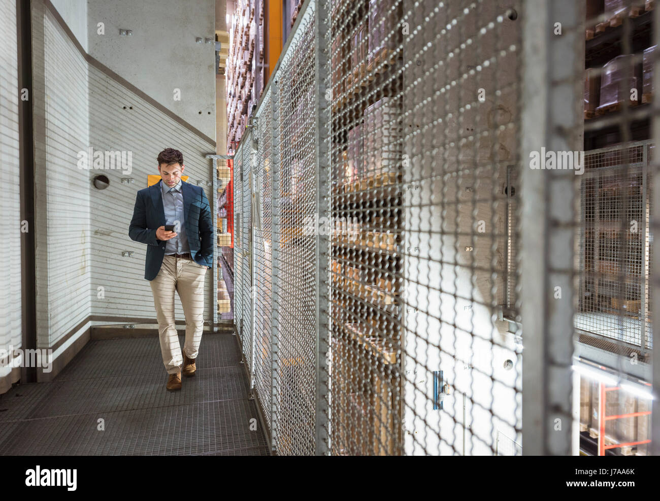 Man in automatized high rack warehouse looking at cell phone Stock ...