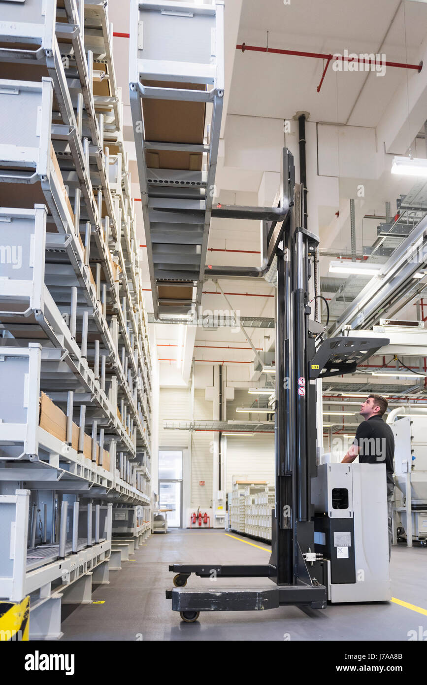 Worker operating forklift in factory warehouse Stock Photo - Alamy