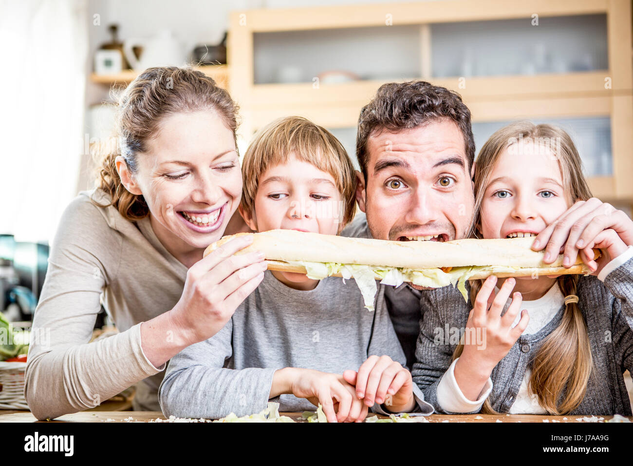 Family in kitchen eating baguette together Stock Photo - Alamy