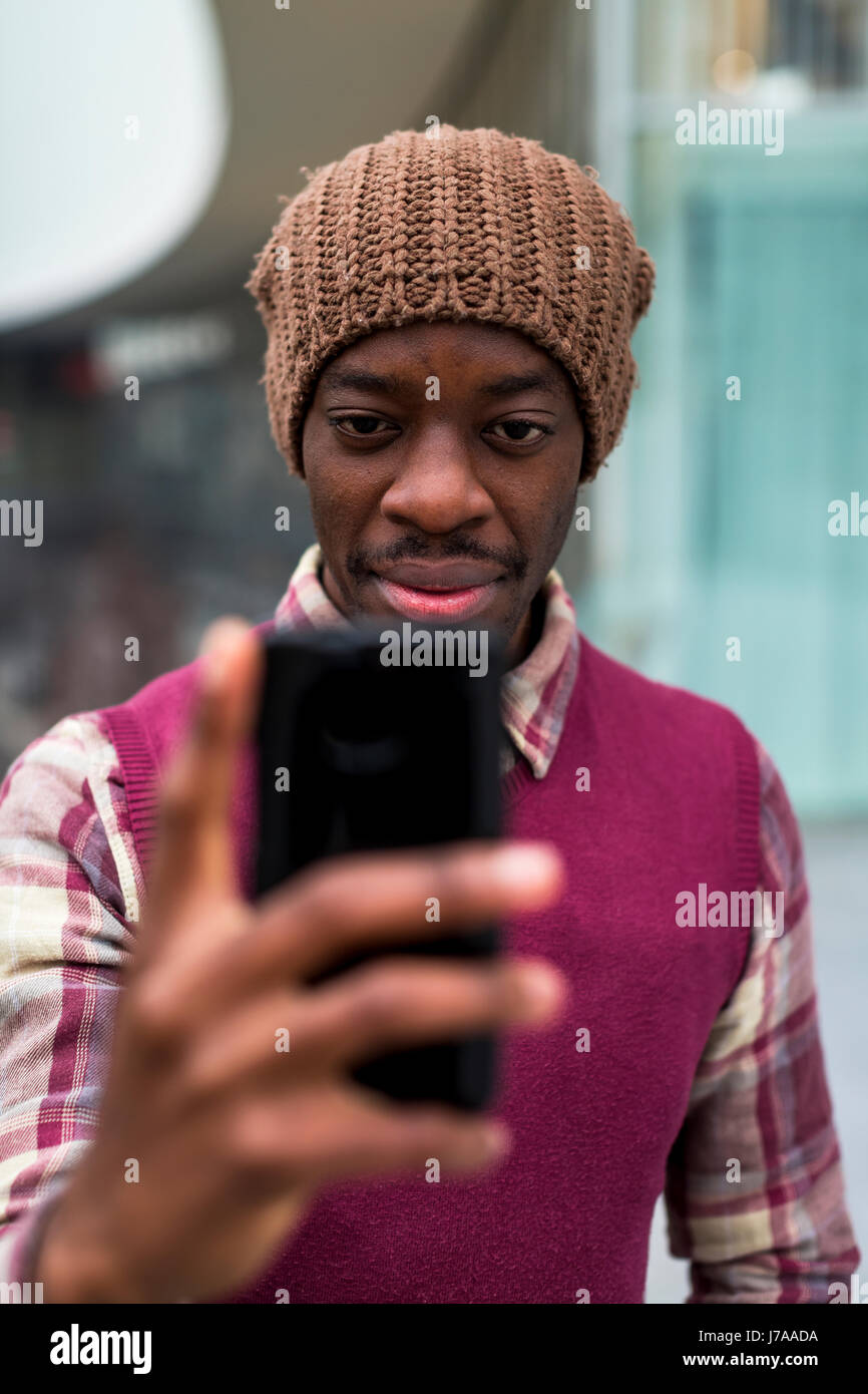 Young man holding cell phone outdoors Stock Photo - Alamy