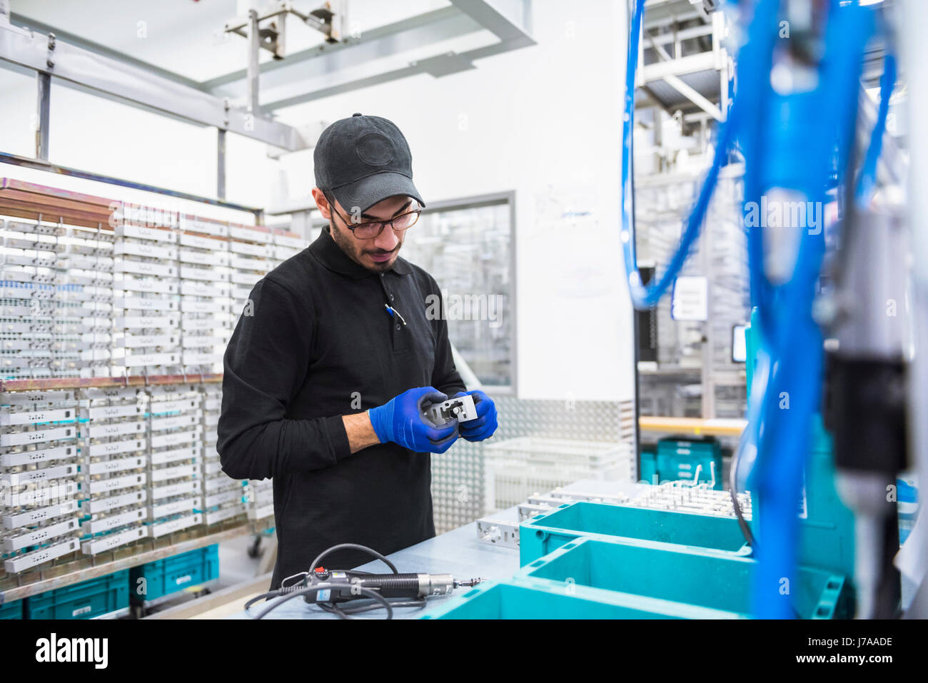 Man working in factory shop floor looking at product Stock Photo - Alamy
