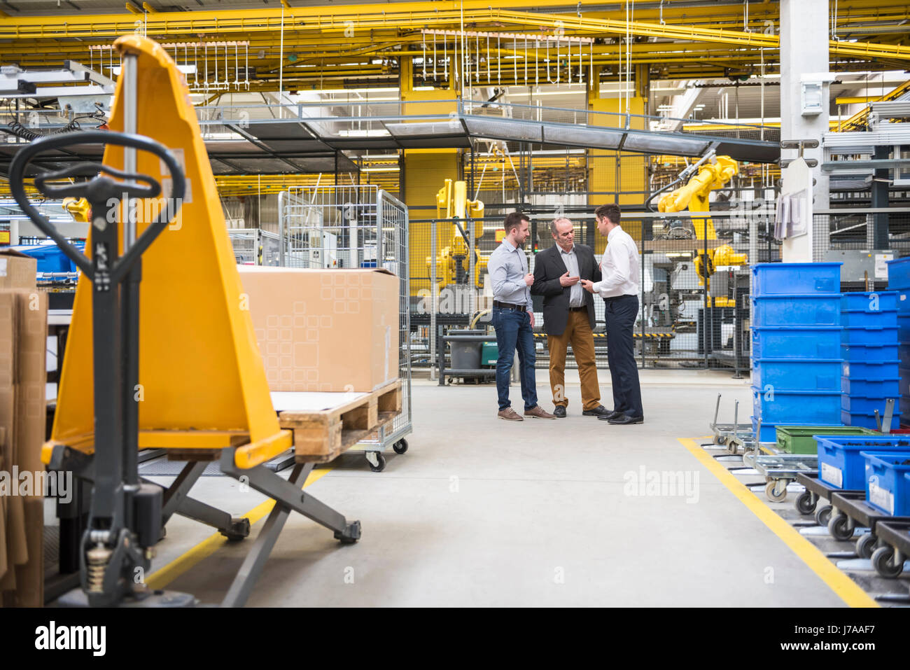 Three men talking in factory shop floor Stock Photo - Alamy