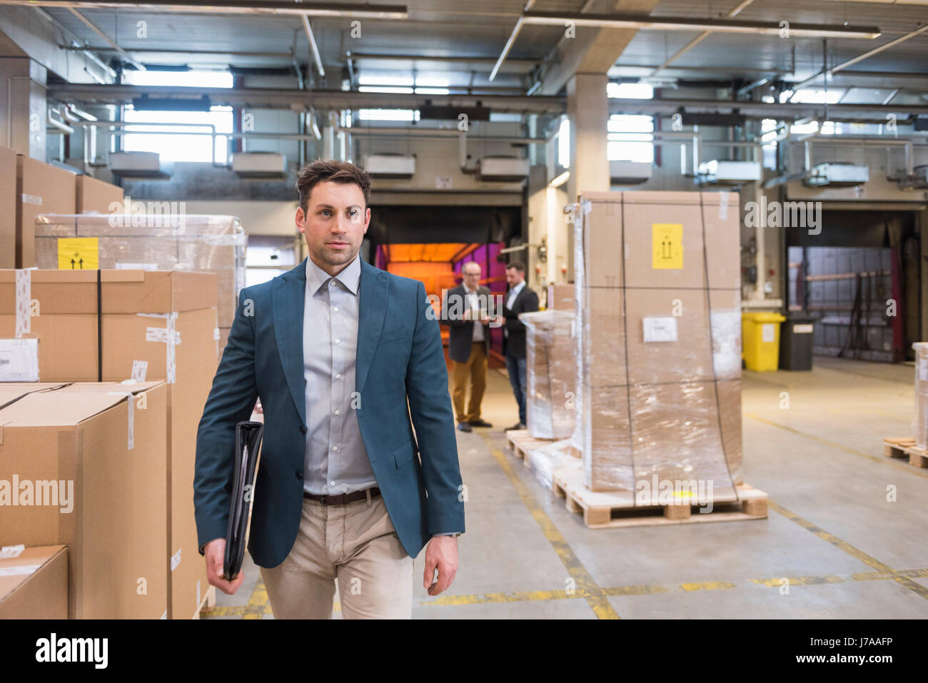 Three men in factory warehouse Stock Photo - Alamy